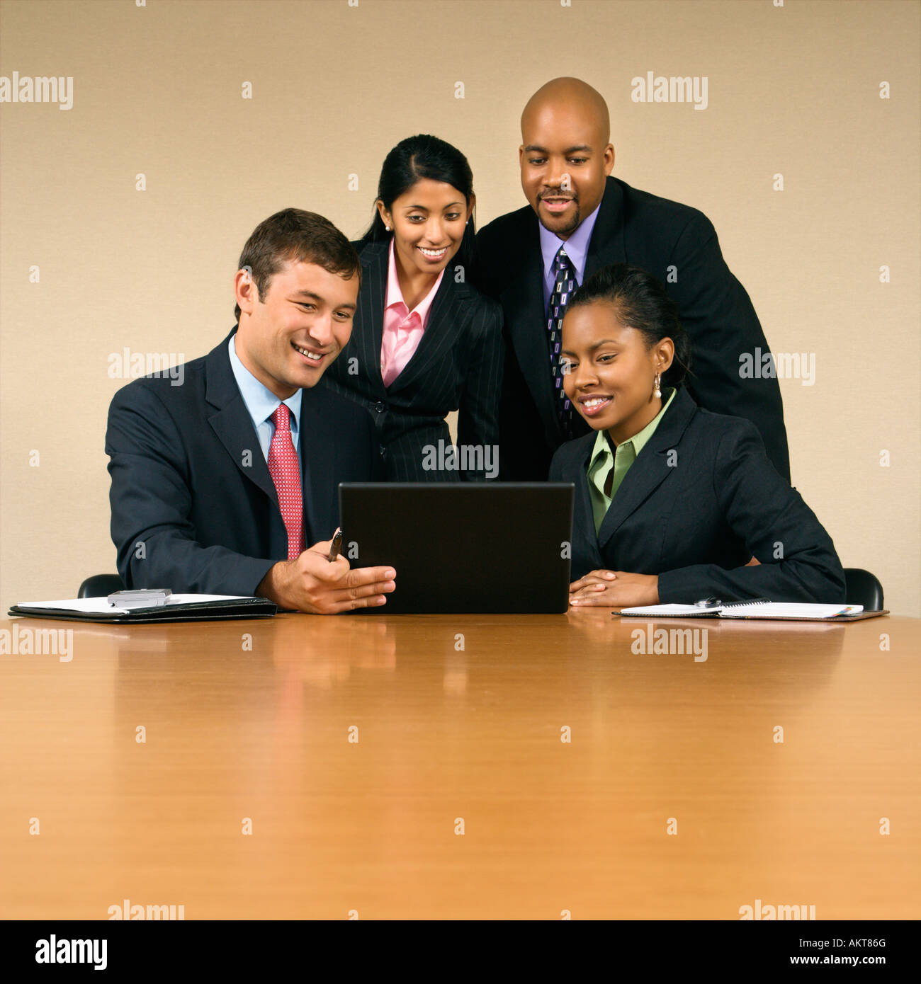 Businesspeople gathered around laptop computer looking at monitor and ...