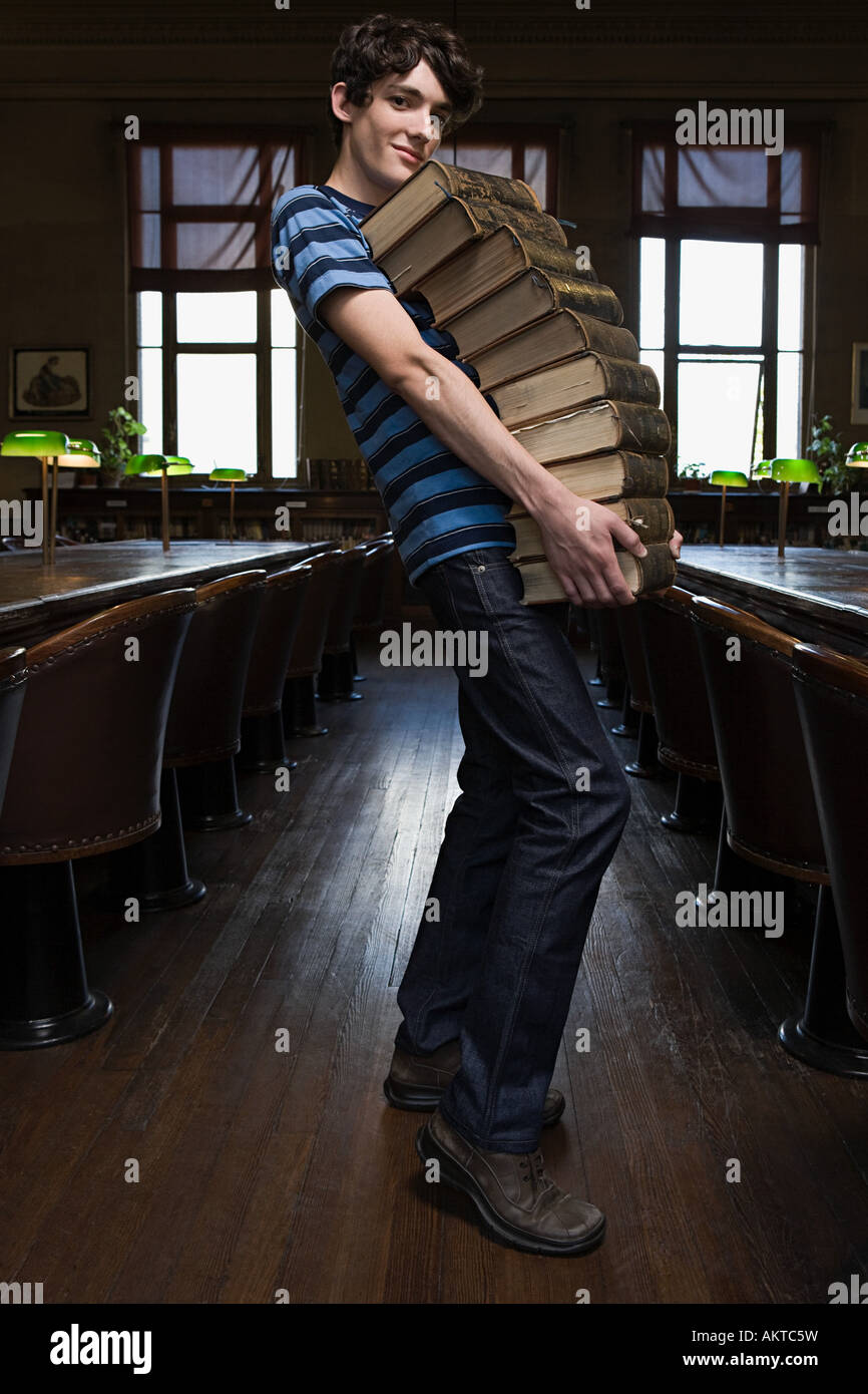 Boy carrying a stack of books Stock Photo - Alamy