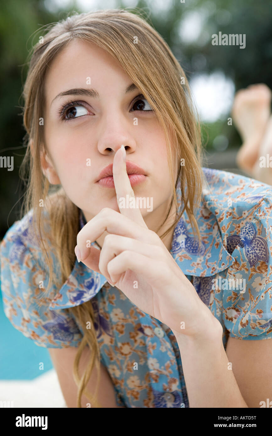 Young woman putting finger to lips Stock Photo - Alamy