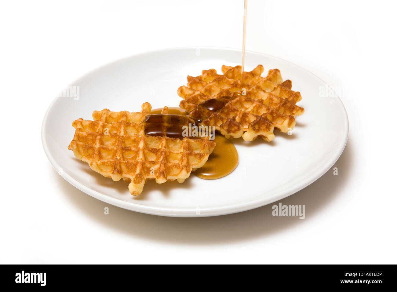 Belgian butter waffles and maple syrup on a white plate and background ...
