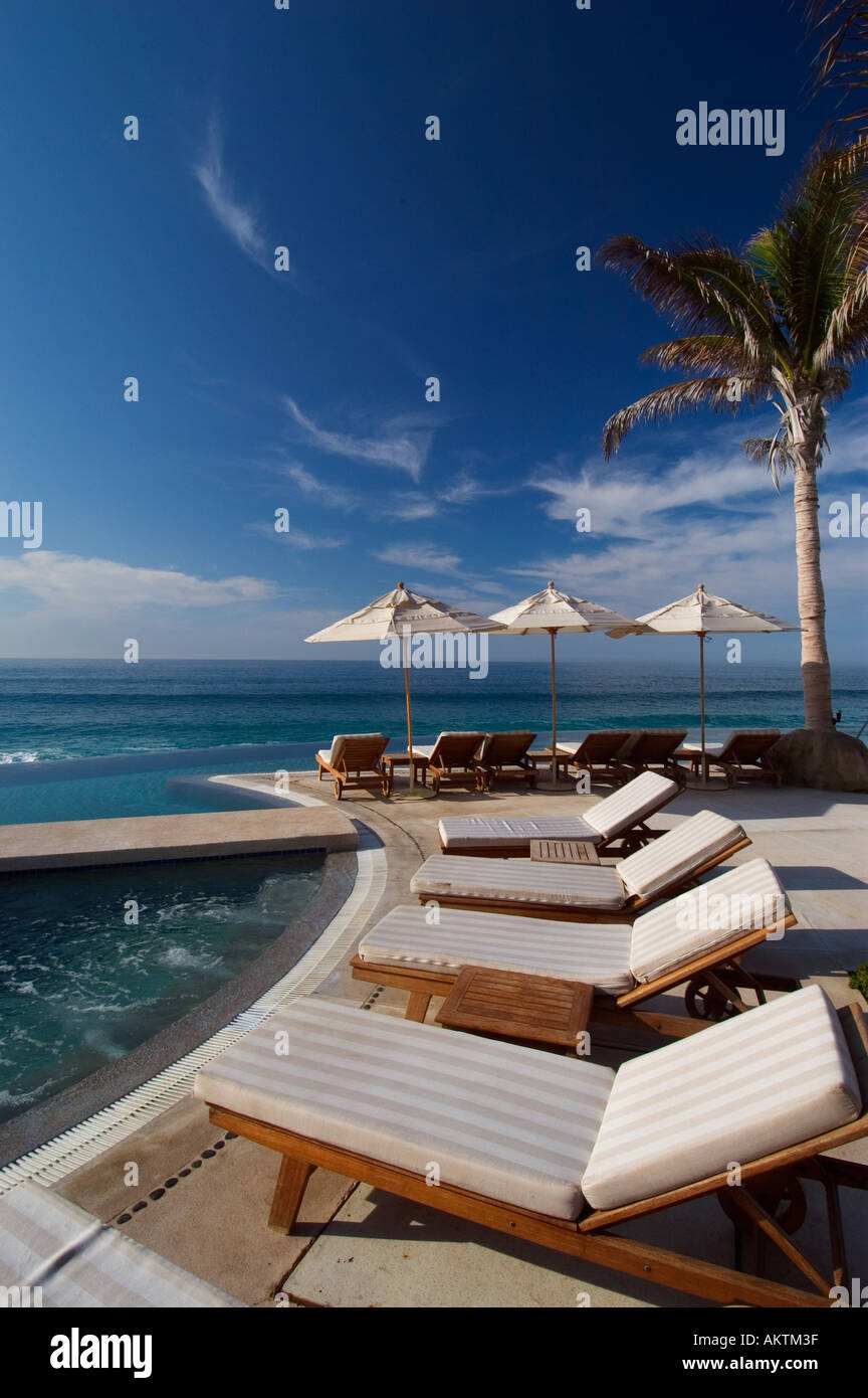 Empty lounge chairs on infinity pool overlooking ocean Stock Photo - Alamy