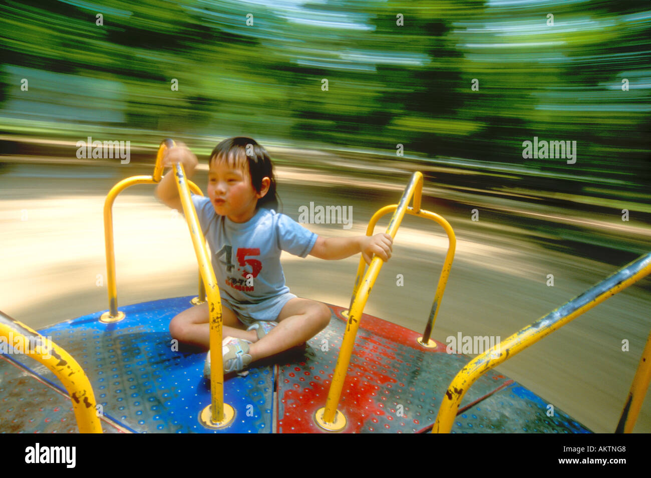 Young girl playing on a spinning playground toy Stock Photo - Alamy