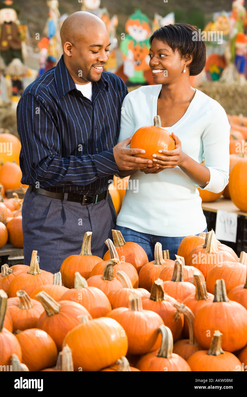 Couple picking out pumpkins and smiling at outdoor market Stock Photo ...