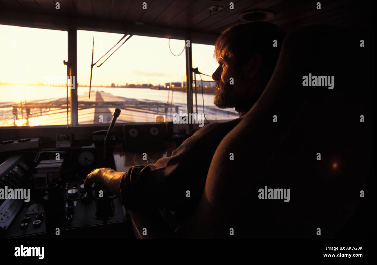 Inland shipping on the Dutch rivers a shipper steering in the cockpit ...