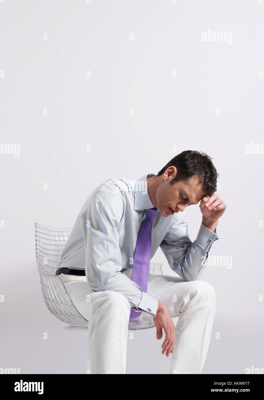 Man sitting in chair with head in hand in studio Stock Photo - Alamy