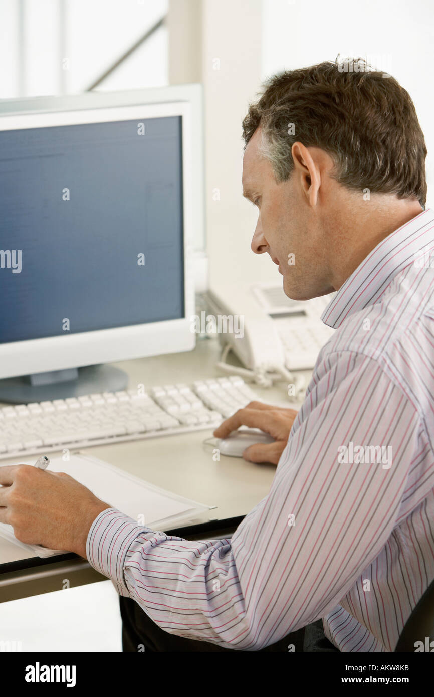 Middle-aged male office worker sitting in cubicle writing Stock Photo - Alamy