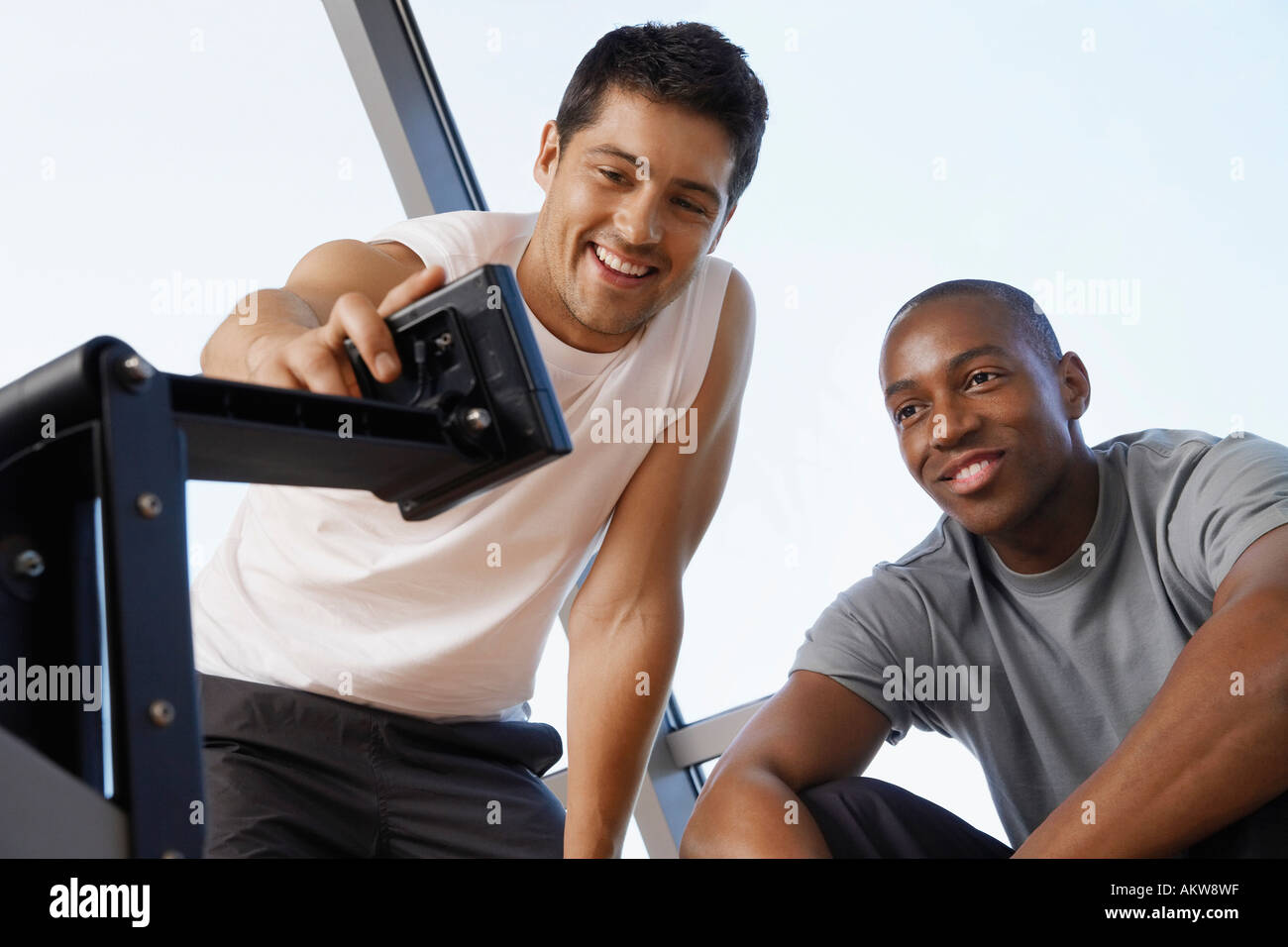 Man showing another man how to use control panel of exercise machine ...
