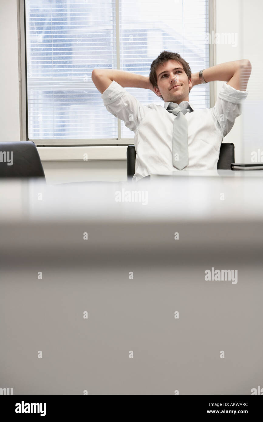 Businessman reclining in office chair looking at ceiling daydreaming ...