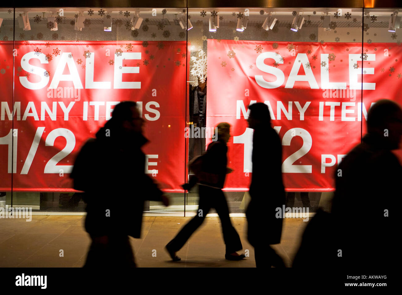 Sale signs in shop window display as shoppers walk by Stock Photo - Alamy