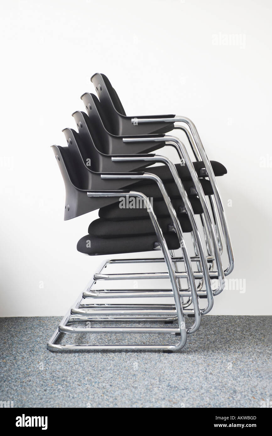 Stack of office chairs against wall Stock Photo - Alamy