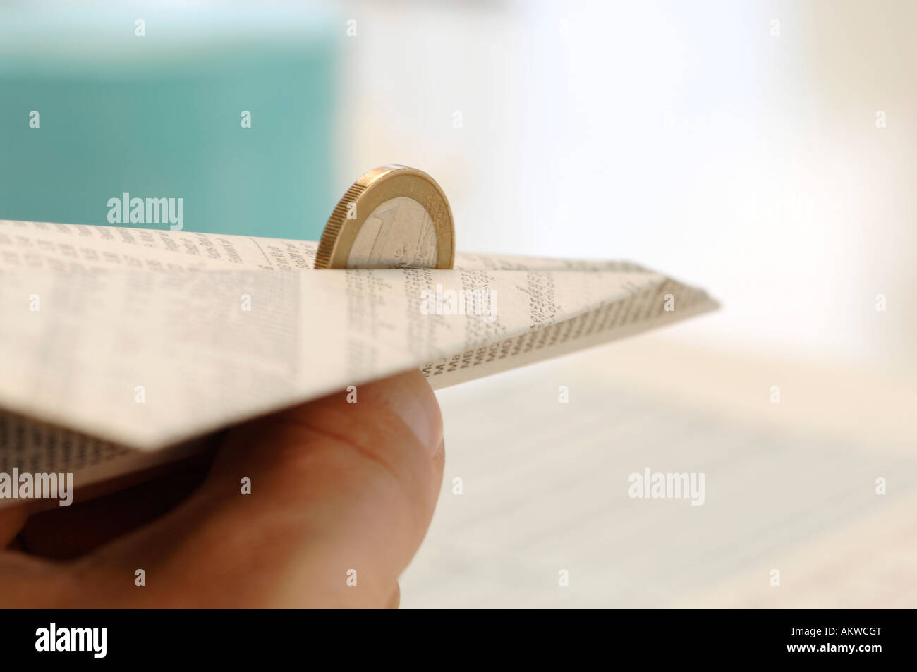 Hand holding euro coin on paper plane, close-up Stock Photo - Alamy
