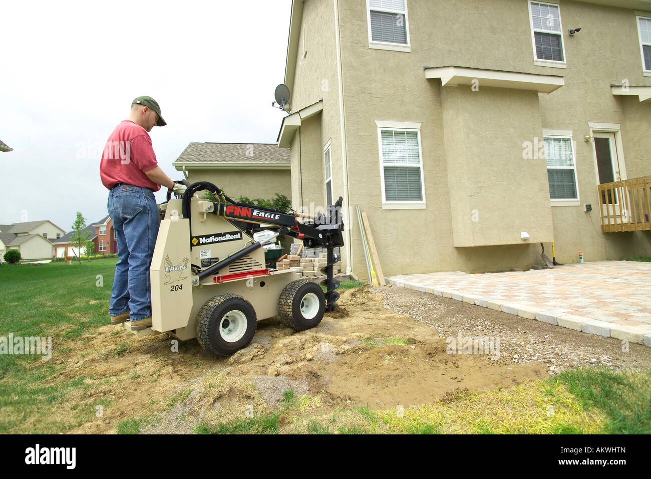 Homeowner digging post holes near new patio with rental equipment Stock ...