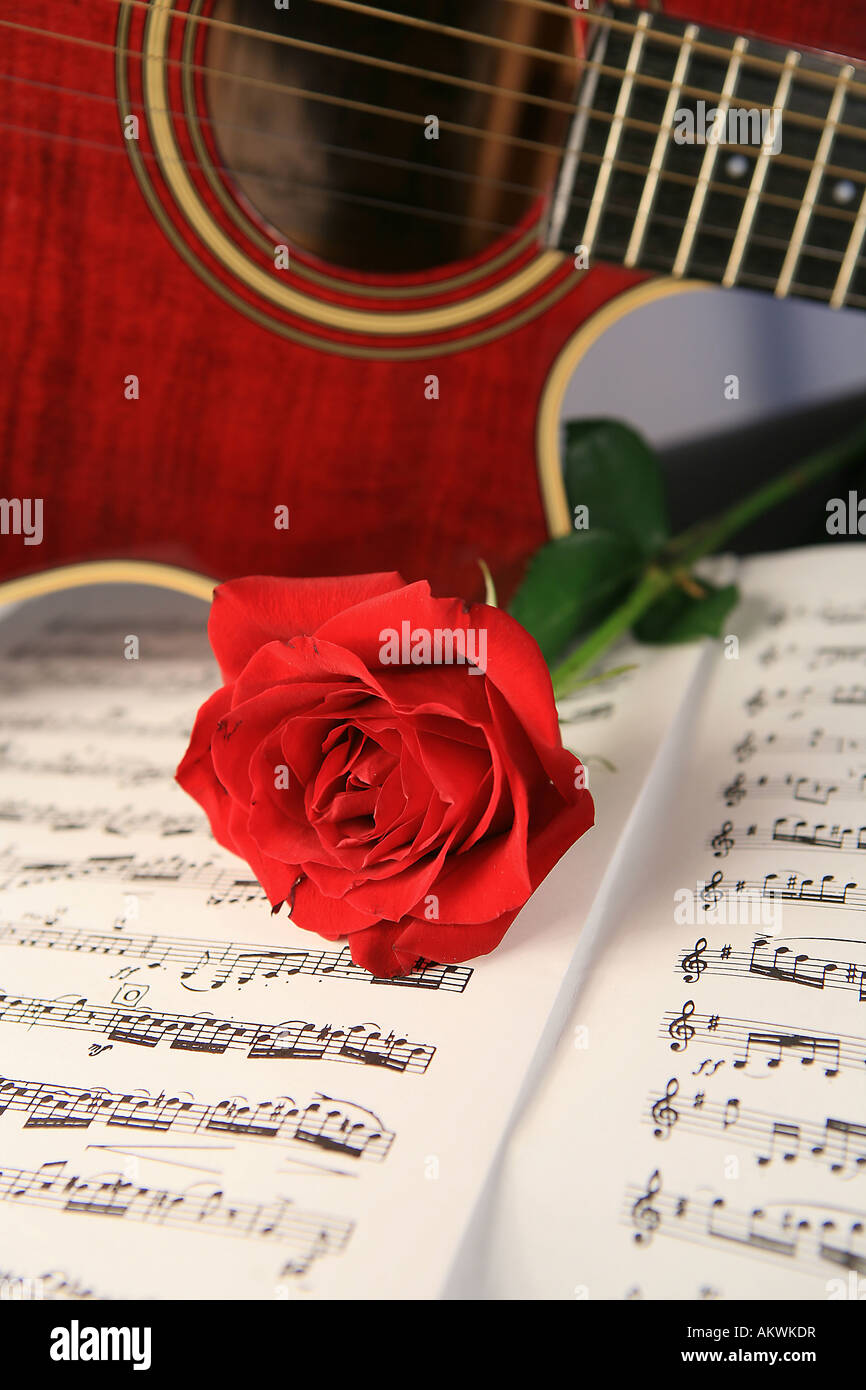 Red acoustic guitar with red rose and sheet music Stock Photo - Alamy