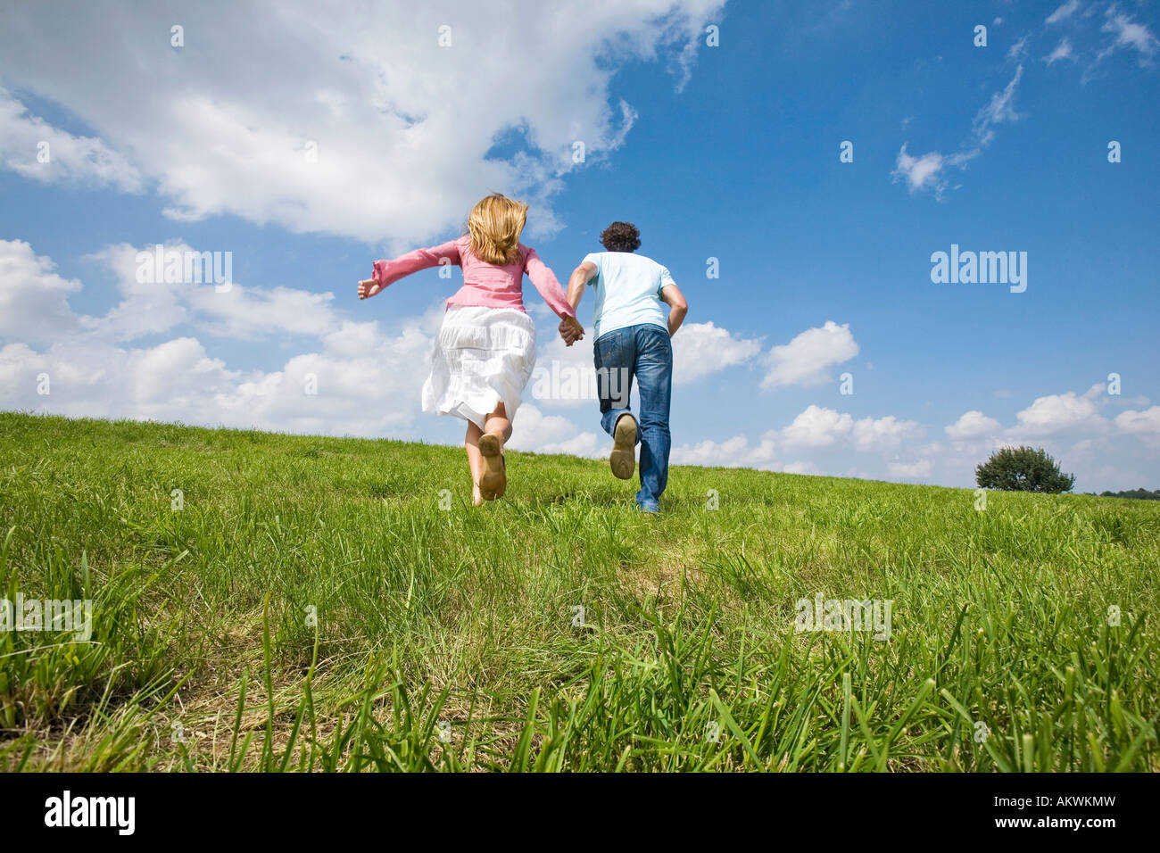 Couple running hand in hand, rear view Stock Photo - Alamy