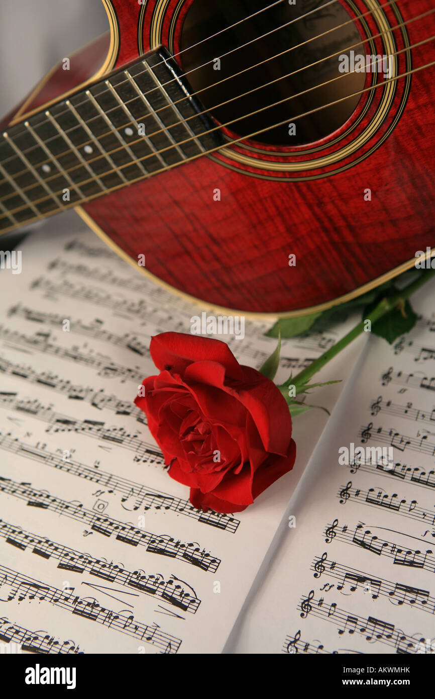 Red acoustic guitar with red rose and sheet music Stock Photo - Alamy