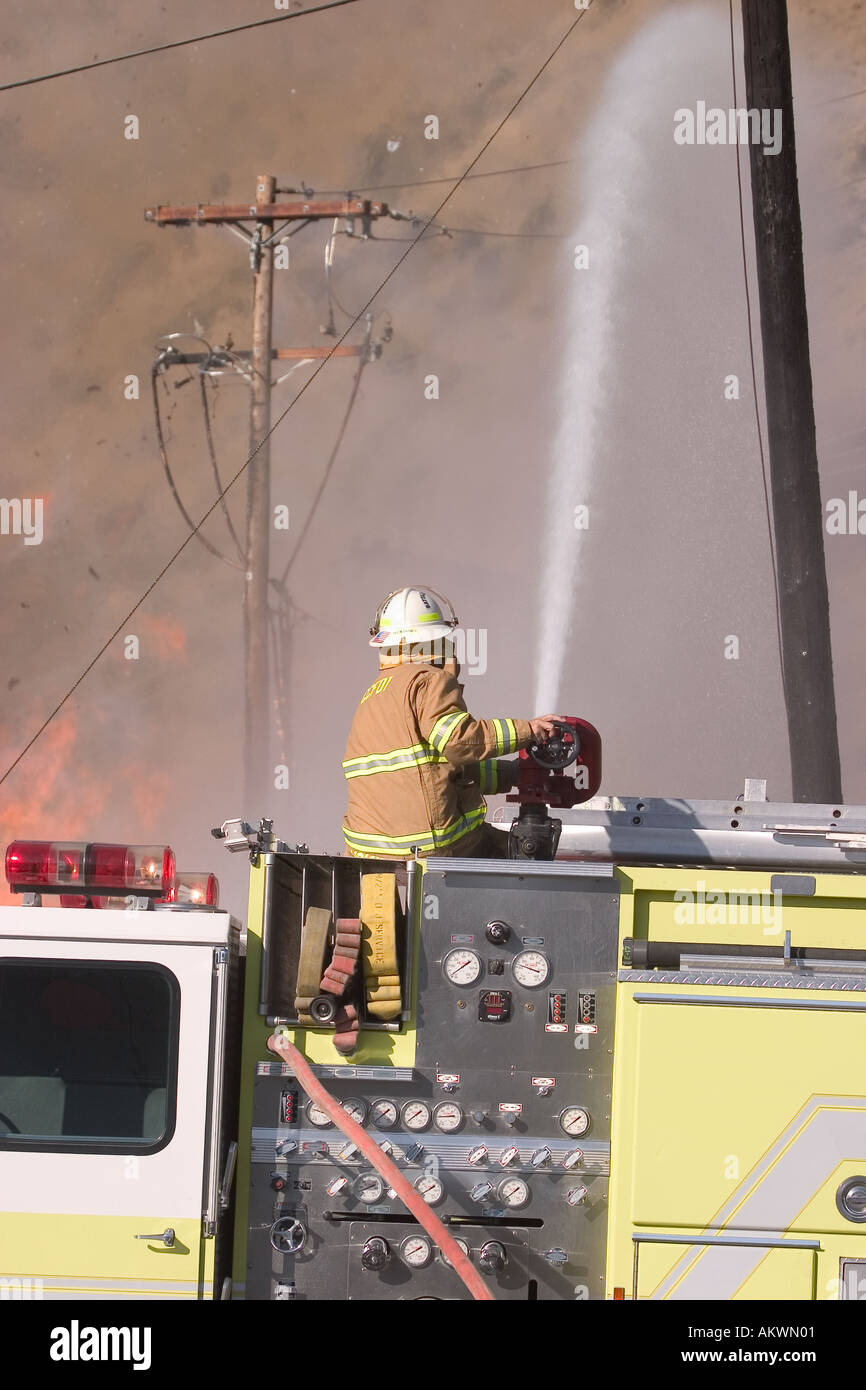 Water being sprayed on a large industrial fire from nozel on fire truck ...