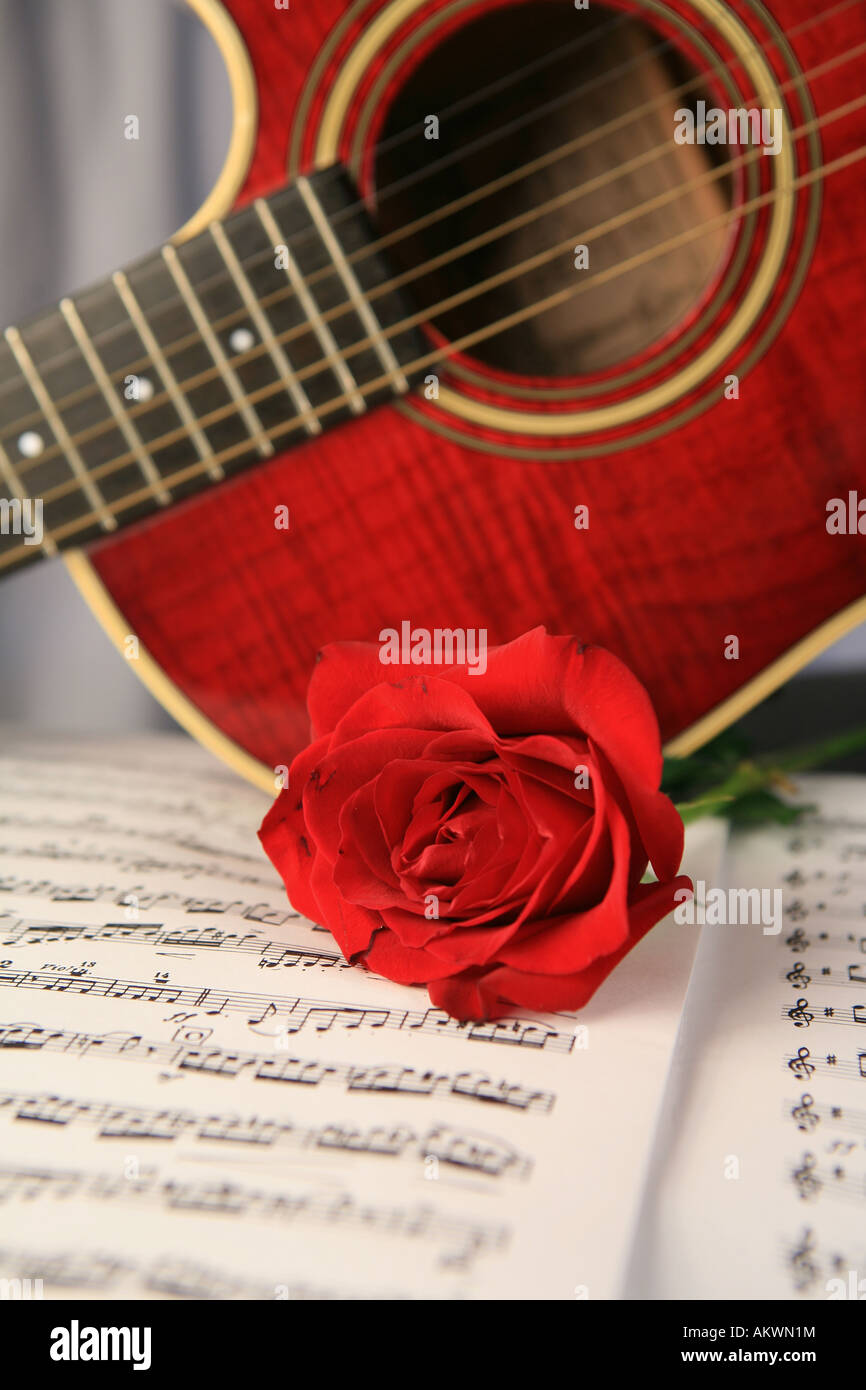 Red acoustic guitar with red rose and sheet music Stock Photo - Alamy