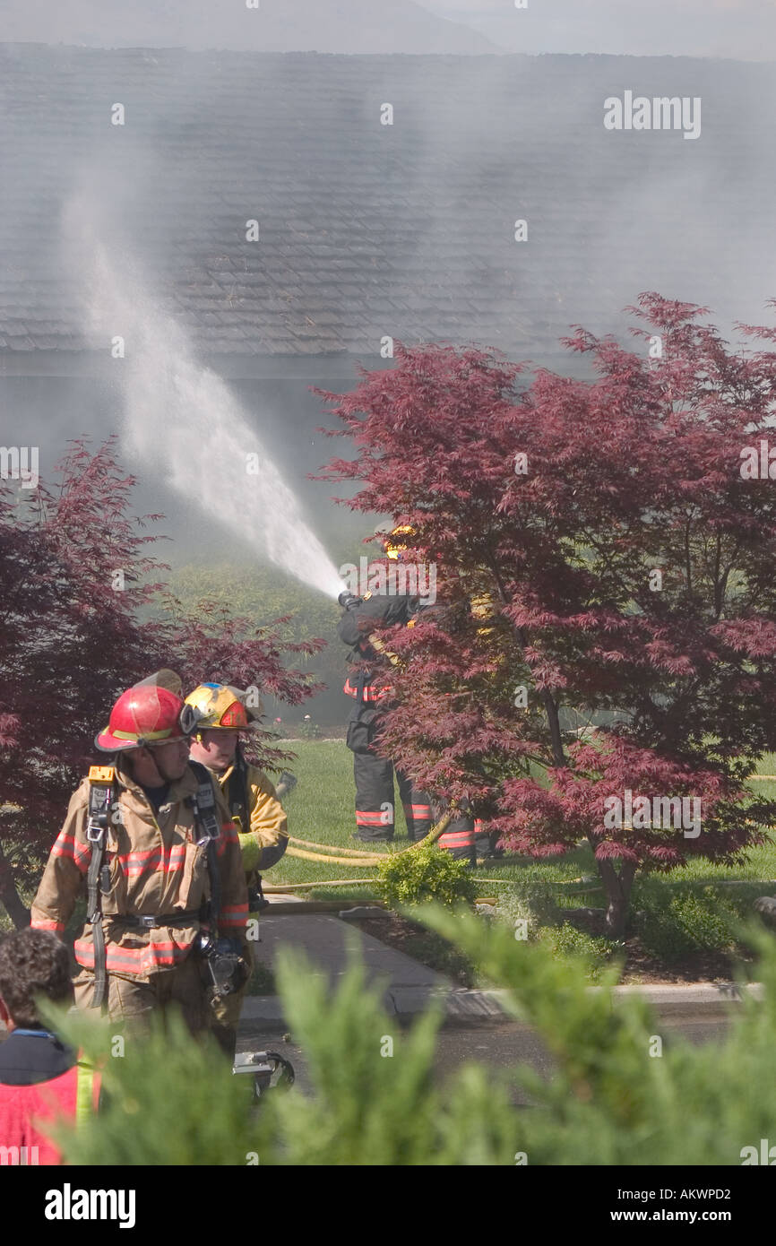 Fireman spraying water on a house fire with smoky background Stock ...