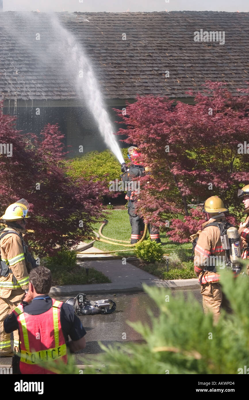 Fireman spraying water on a house fire with smoky background Stock ...