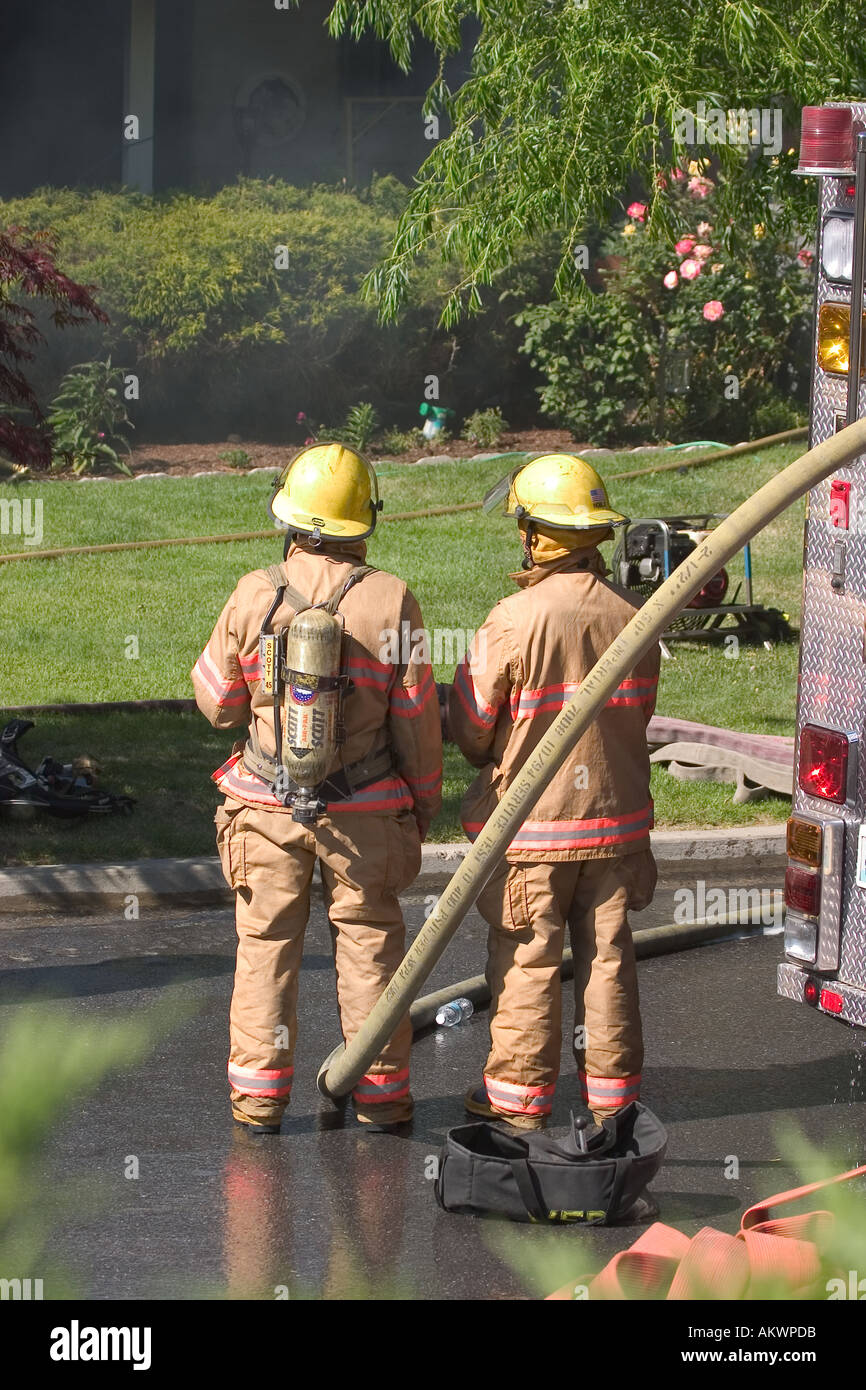 Two firemen at the scene of a house fire Stock Photo - Alamy