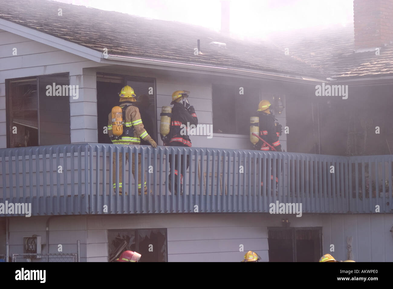Firemen walking on a deck at a house fire with smoky background Stock ...