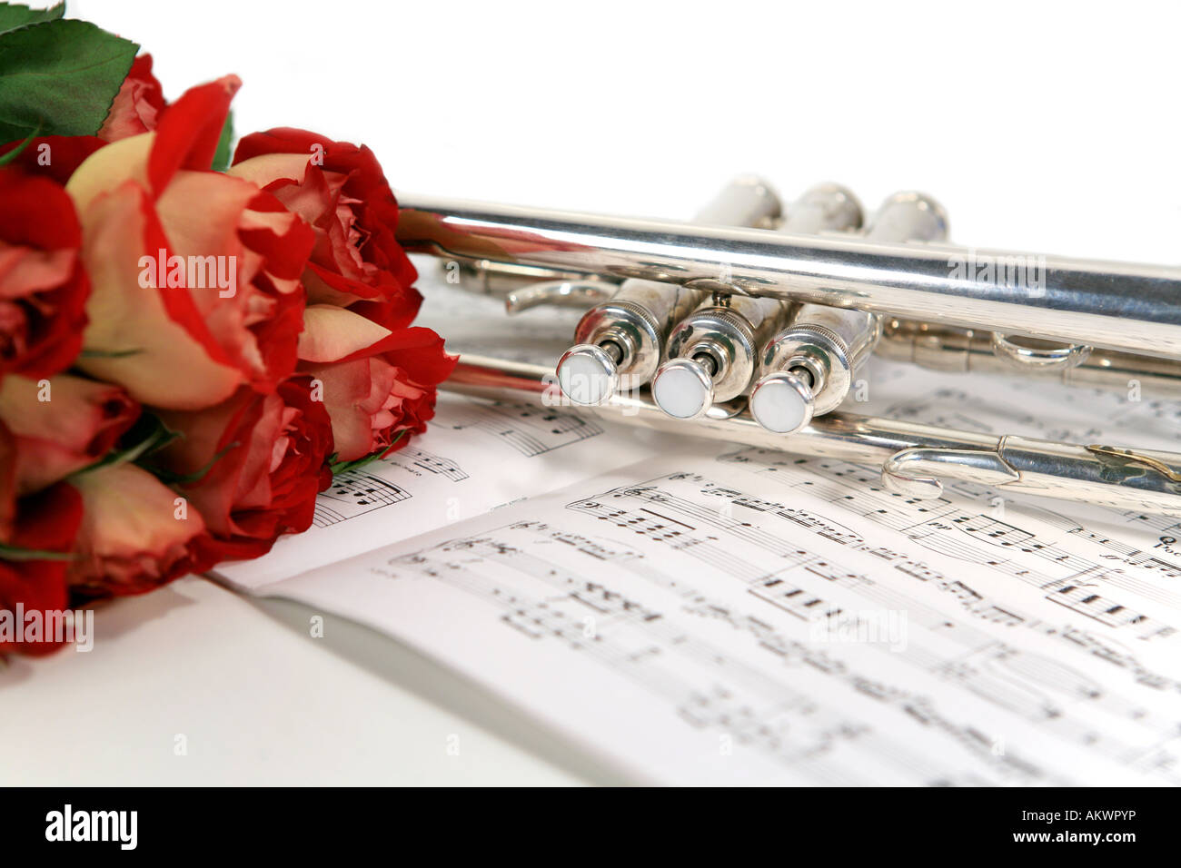 Silver trumpet with bouquet of roses on top of sheet music Stock Photo ...