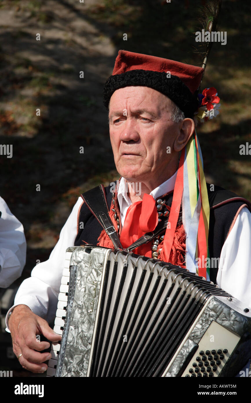 An old man in military uniform plays an accordion for tourists at ...