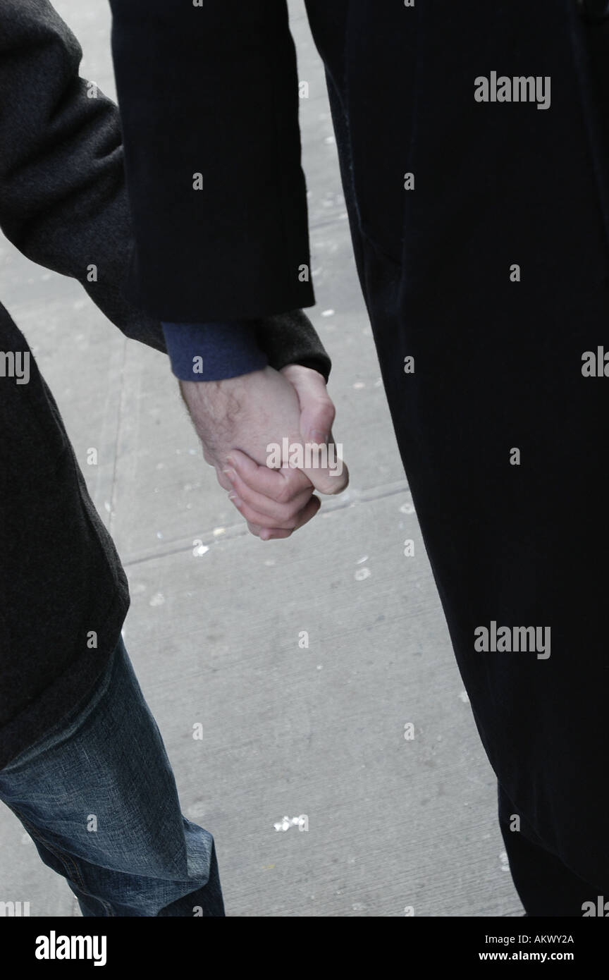 A couple in dark coats holding hands while walking Stock Photo - Alamy