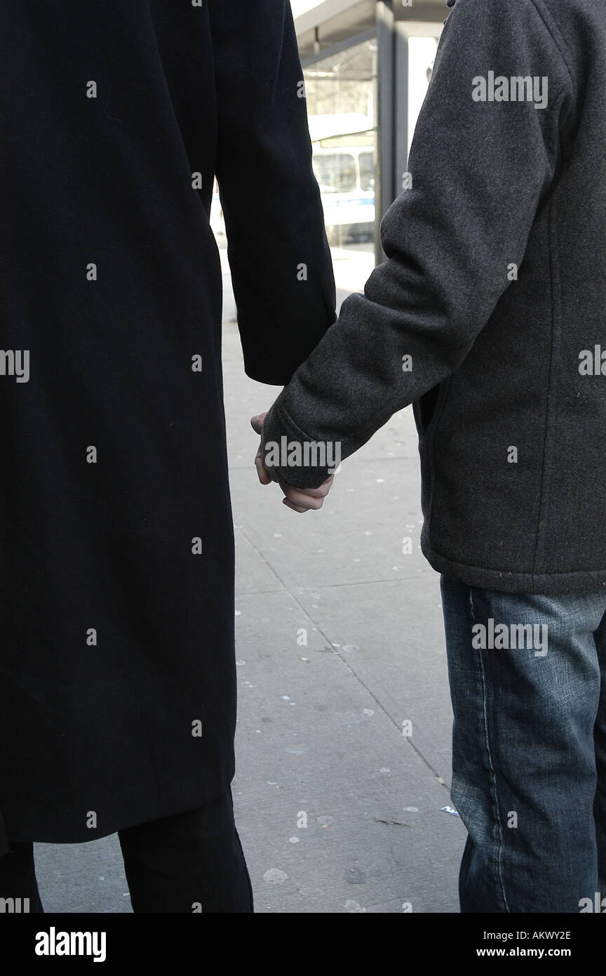 A couple in dark coats holding hands while walking Stock Photo - Alamy