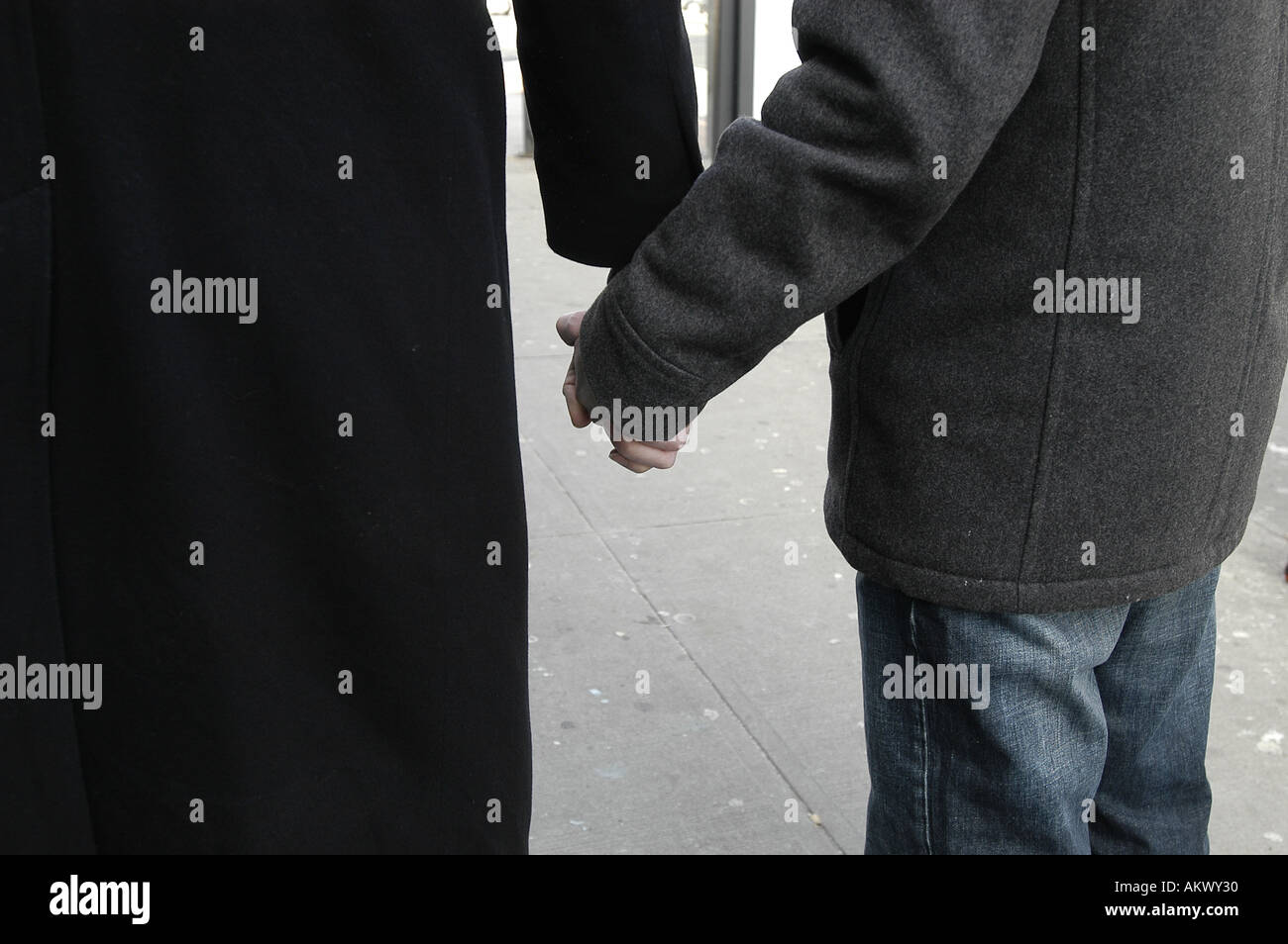 A couple in dark coats holding hands while walking Stock Photo - Alamy
