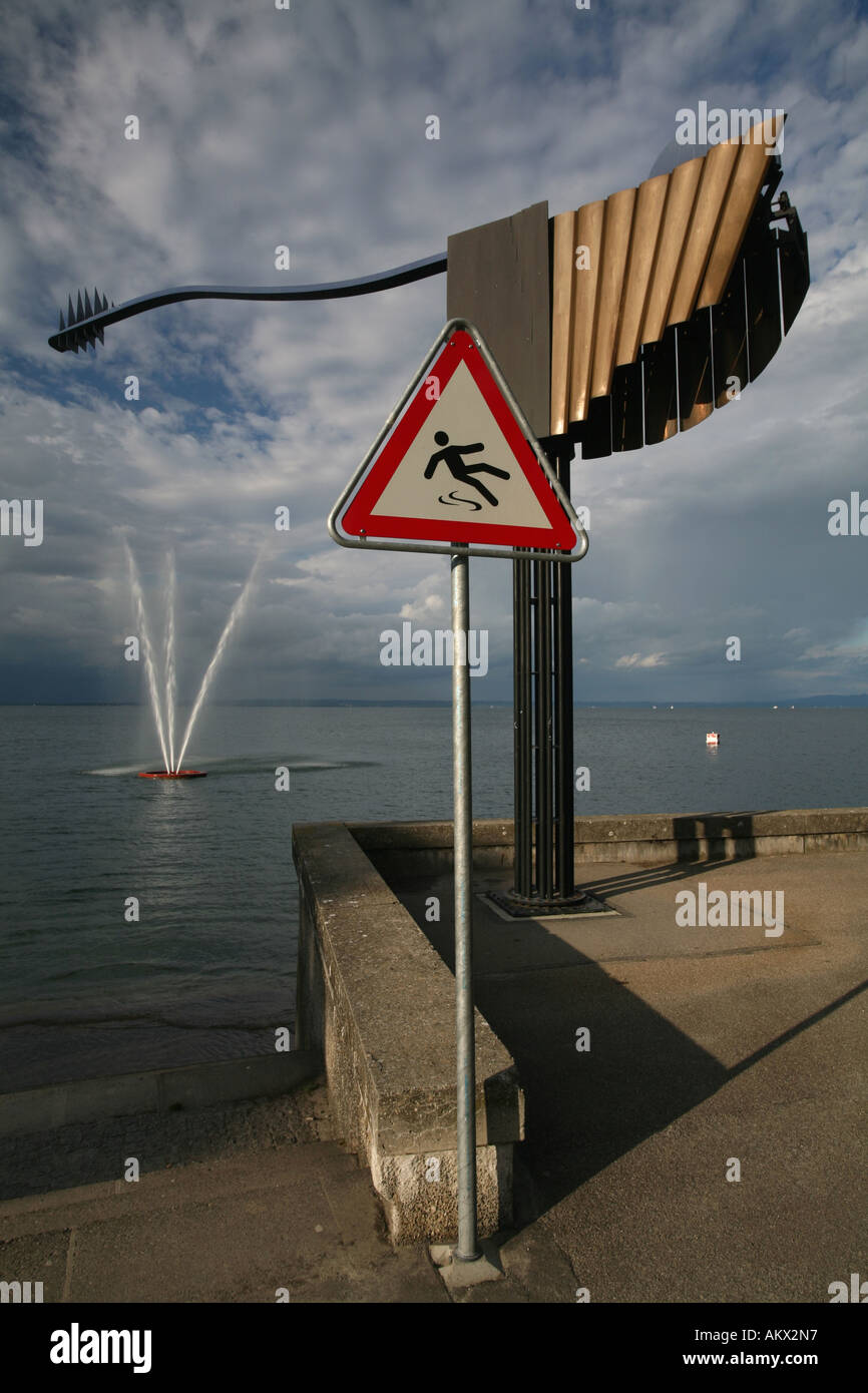 Sign warns of slipping danger, water fountain in the background and ...