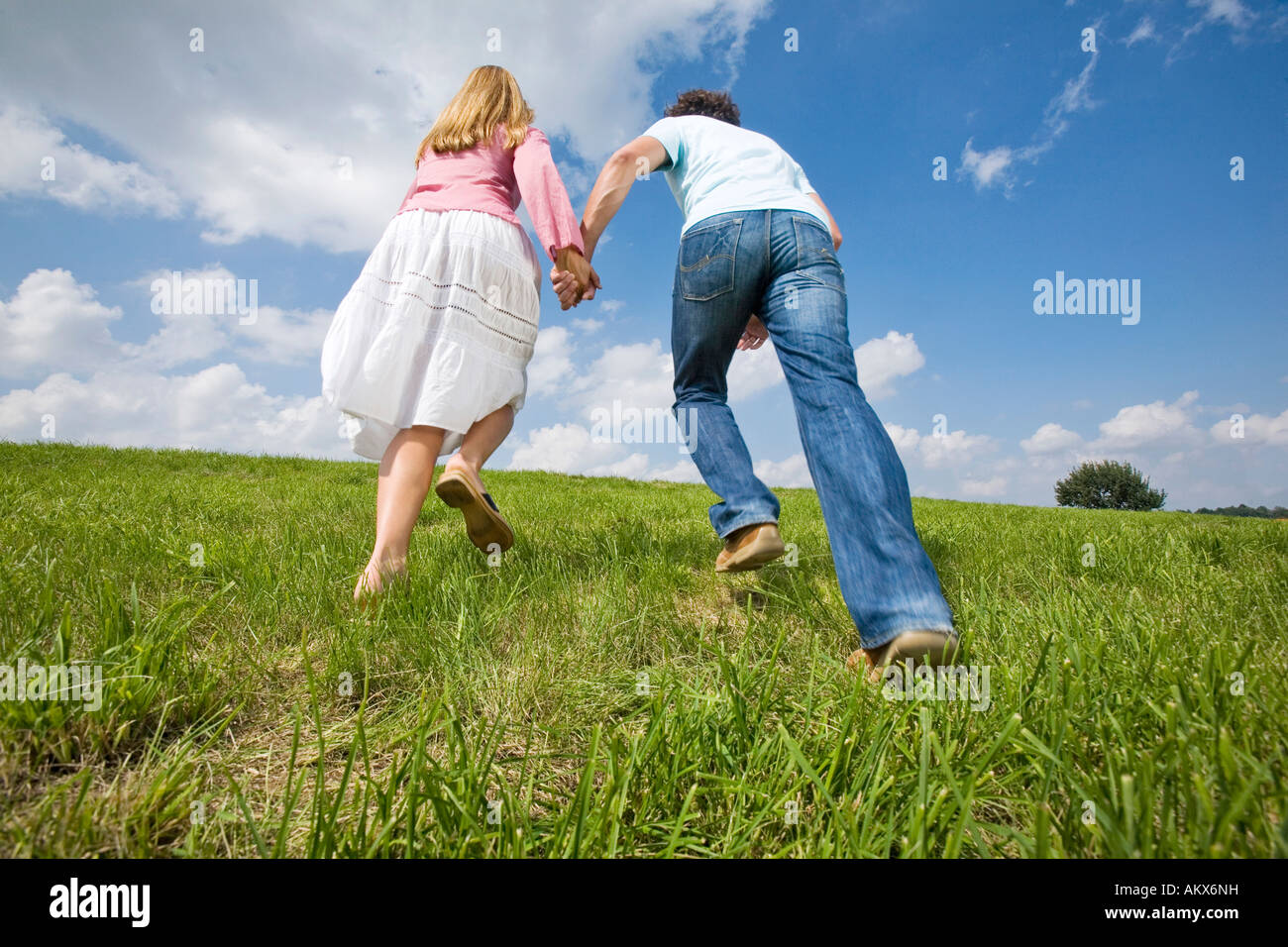 Couple running hand in hand, rear view Stock Photo - Alamy