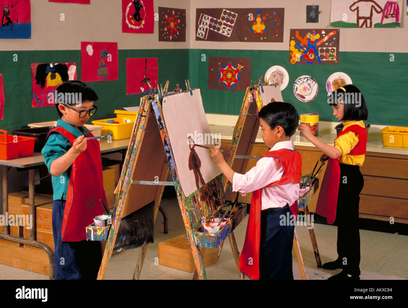 THREE SECOND GRADE STUDENTS WORKING ON THEIR PAINTINGS IN THE ART CLASS ...