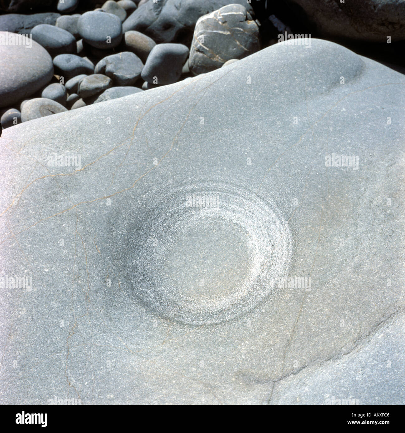 Abstract of evaporated salt circle on pale rock with beach pebbles on ...