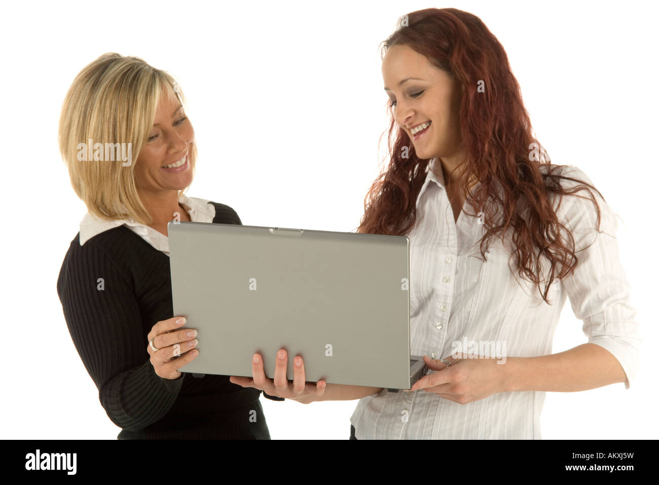 Two young women studying a laptop computer in an office environment ...