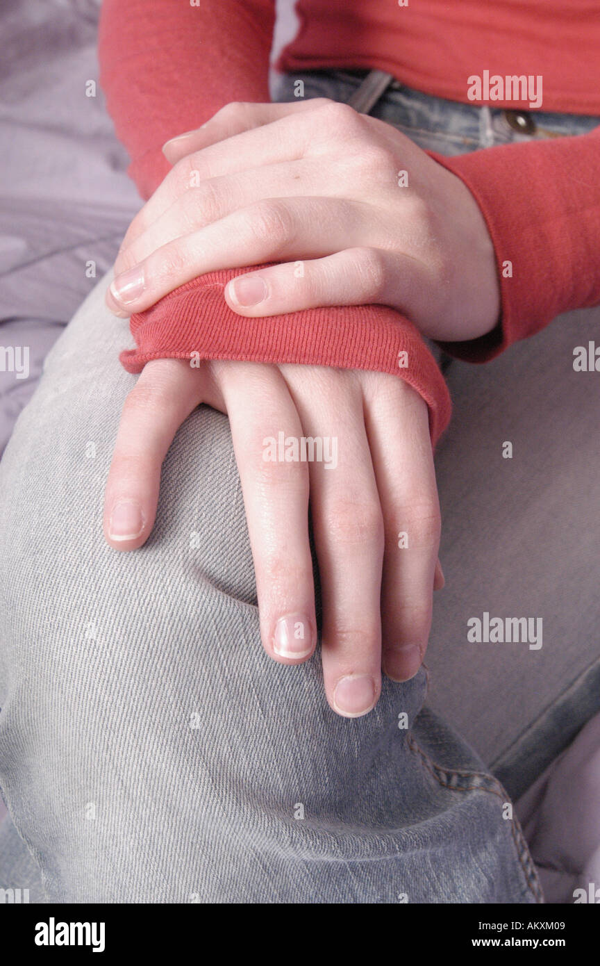 Folded hands resting on a lap Stock Photo - Alamy