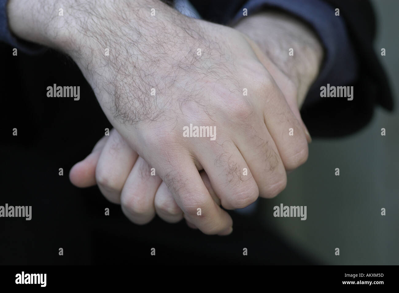 Folded hands resting on a lap Stock Photo - Alamy