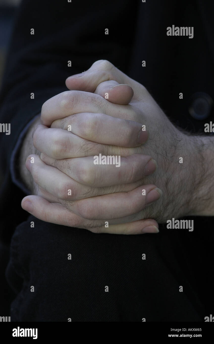 Folded hands resting on a lap Stock Photo - Alamy