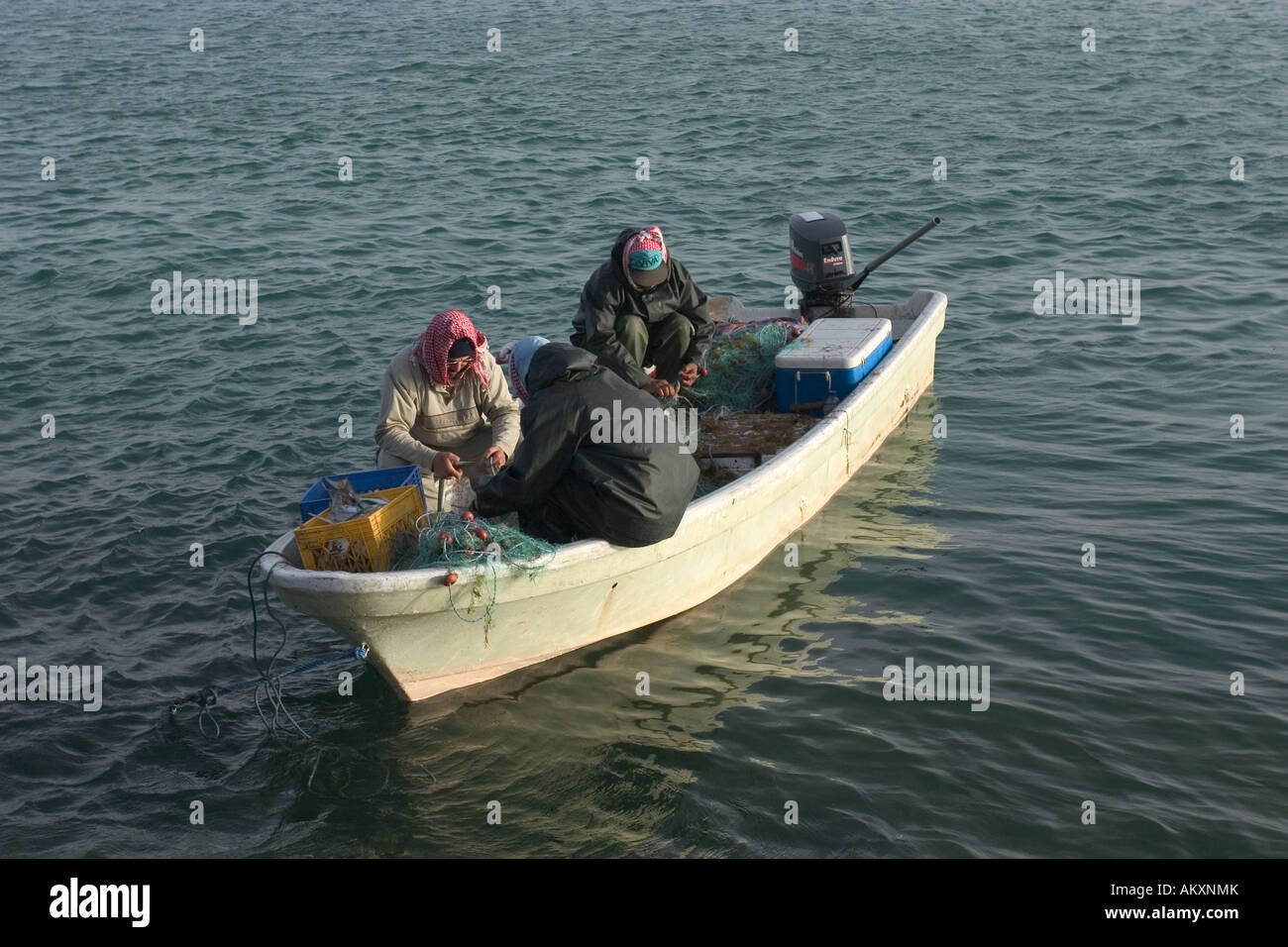 Asian fishermen clearing their nets of the overnight catch next to the ...