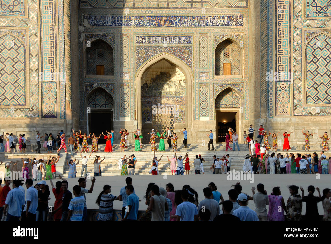 Young women dancing in front of Madrasah Sherdar Registan Samarkand ...
