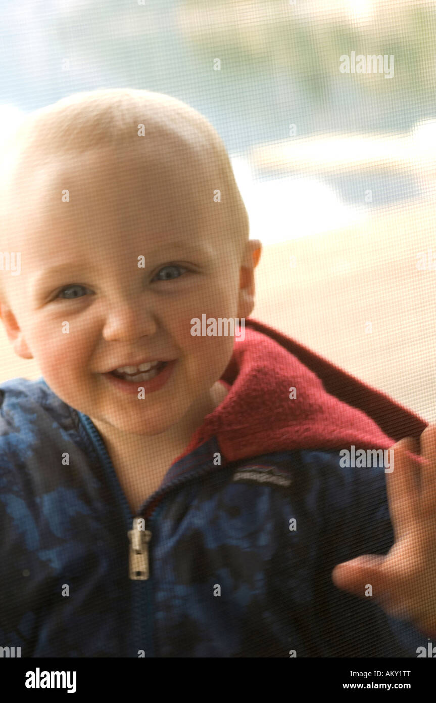 Little boy peeking through screen door Stock Photo - Alamy
