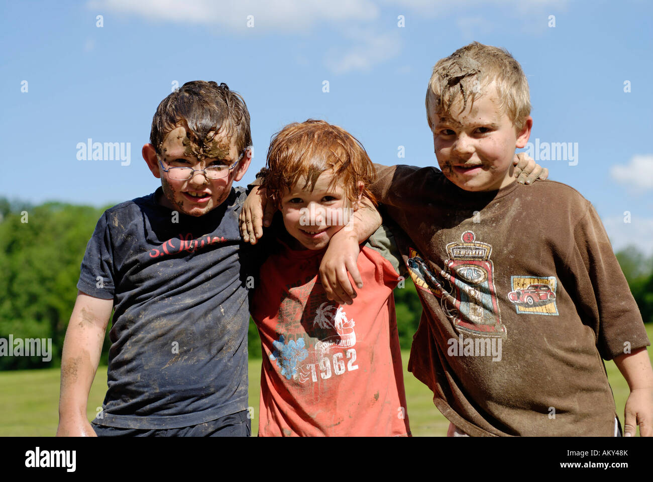 Three friends boys covered with mud and having fun Stock Photo - Alamy
