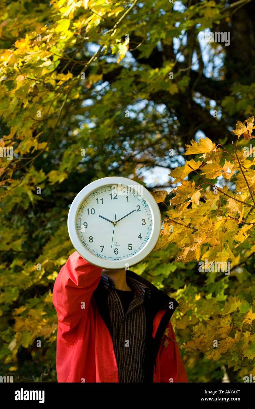 Man is holding a clock in front of his face Stock Photo - Alamy