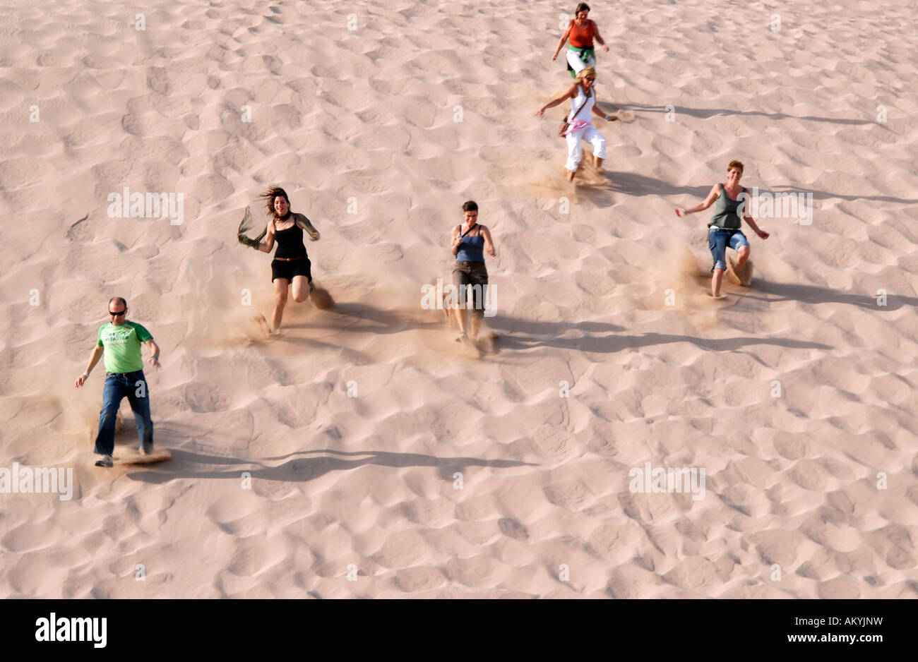 On location in the desert, tourists running down a dune, Hurghada ...