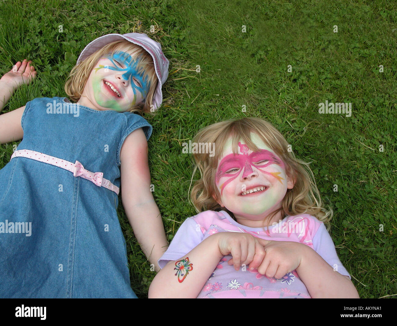 girls with their face painted laying on grass having a laugh Stock ...