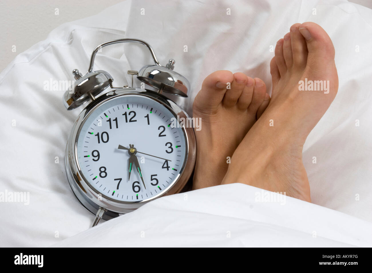 Blanket, feet, alarm clock Stock Photo - Alamy