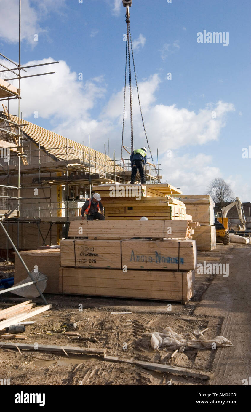 Construction workers handling timber by crane sling Stock Photo - Alamy