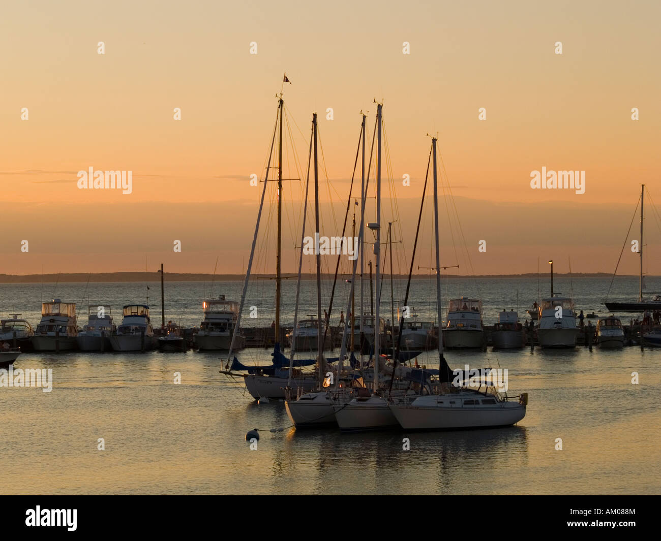 A golden sunset over the boats in the harbour of the fishing village of ...