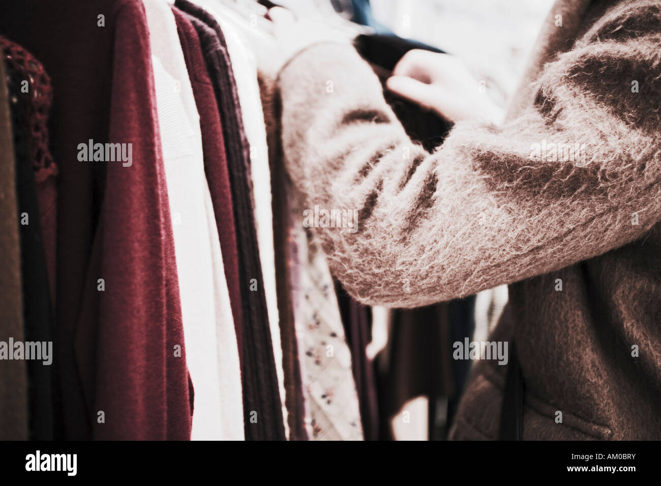 Woman Sifting Through Display Of Clothes Stock Photo - Alamy