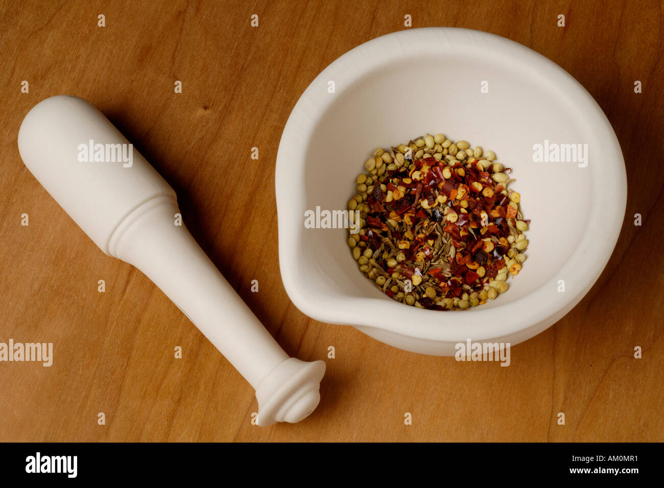 Pestle and mortar with coriander seeds cumin seeds and dried chilli on ...